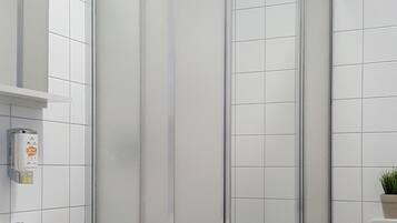 Uma casa de banho moderna com cabine de duche em vidro, lavatório com porta-toalhas e sanita.