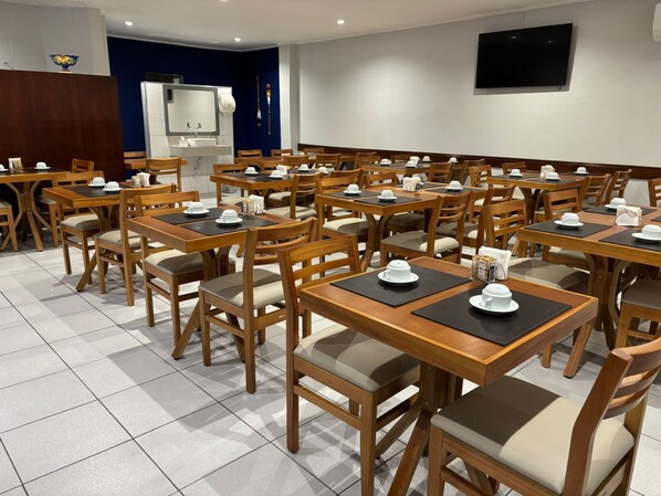 Uma sala de conferências com várias mesas e cadeiras, equipada com placas de identificação e louças postas.