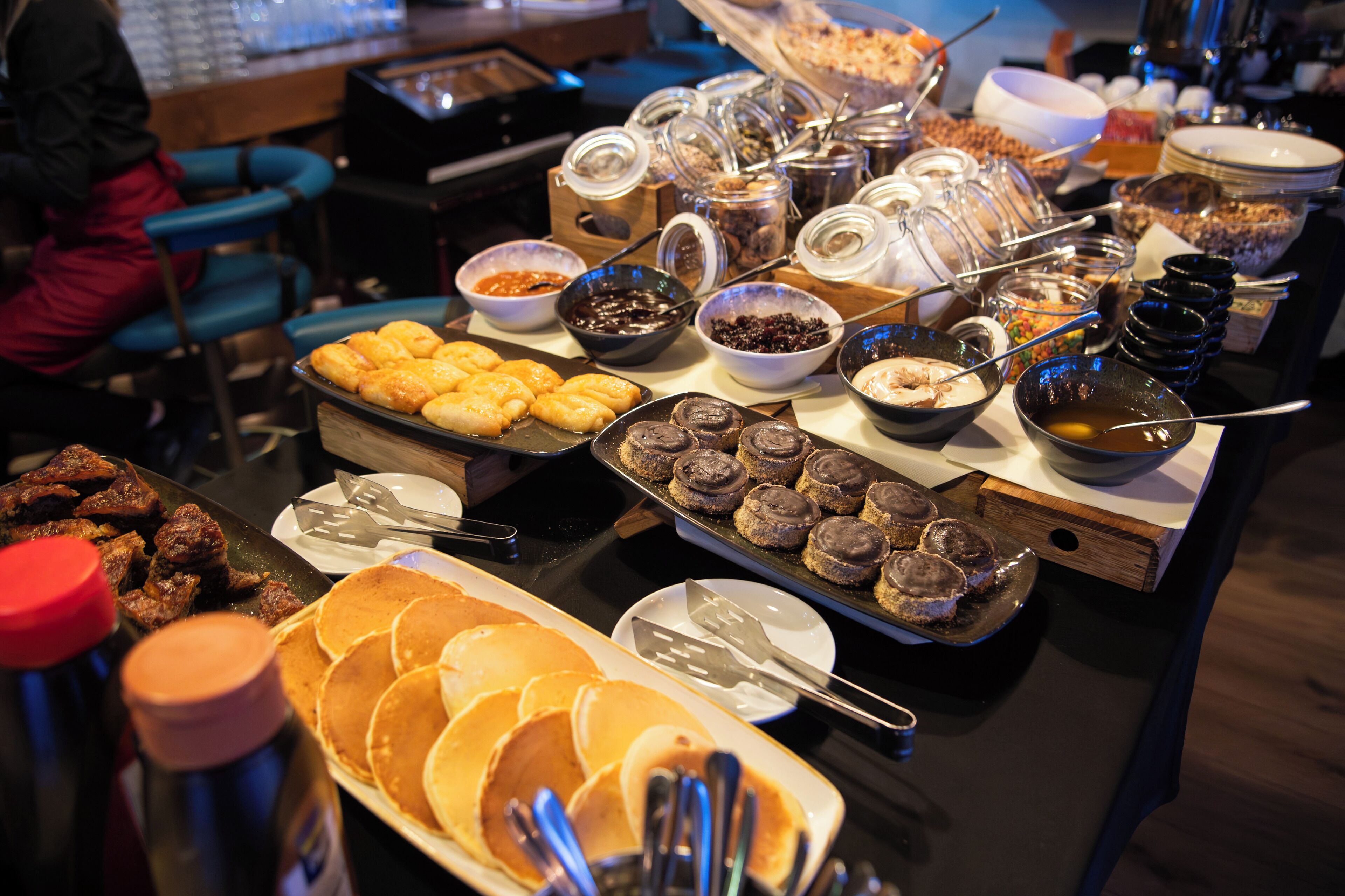 Buffet com diversos pratos, incluindo panquecas, carnes e sobremesas.