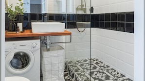 Casa de banho com máquina de lavar roupa, pia e chuveiro.
