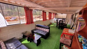 Quarto com piso de grama artificial verde, um sofá, uma mesa de centro de vidro e uma mesa de jantar com cadeiras.