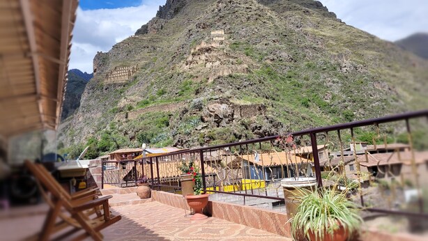 Terraço com vista para as montanhas, mesas ao ar livre e plantas em vasos.