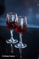 Duas taças de vinho sobre uma superfície refletora.