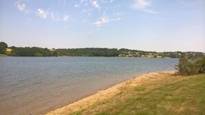 Vista para o lago com uma praia de areia e uma área gramada.