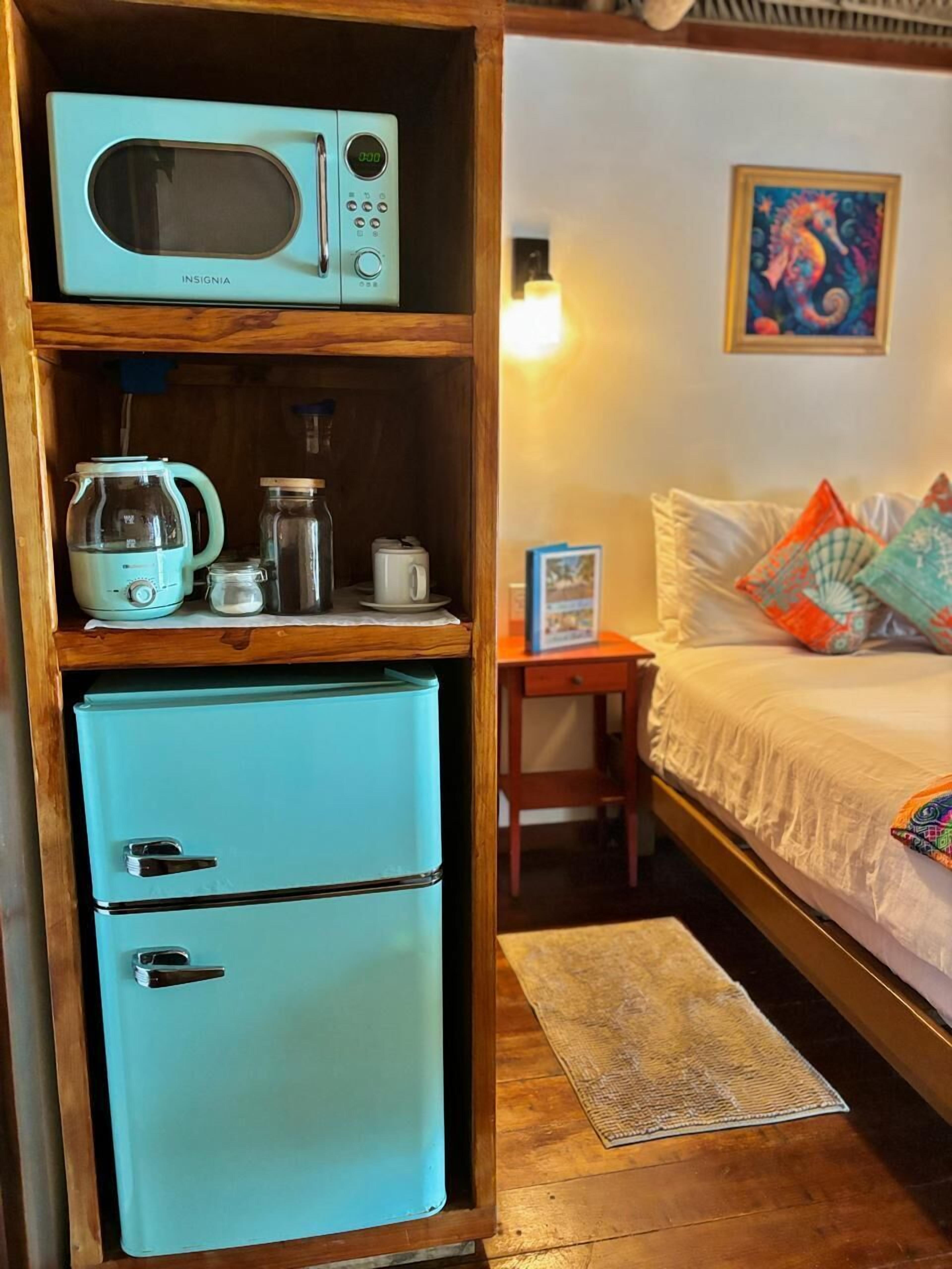 Uma cozinha compacta equipada com micro-ondas, chaleira e mini refrigerador.