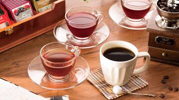 Uma mesa de madeira com três xícaras de chá, um moedor de café e um livro.