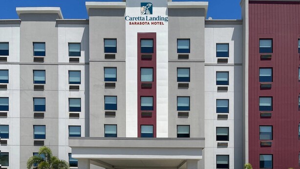Um hotel com vários andares e uma placa chamativa com a inscrição 'Carette Landing Sarasota Hotel'.