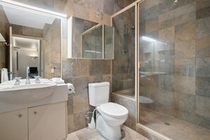 Uma casa de banho moderna com uma grande pia, sanita e cabine de duche com vidro.