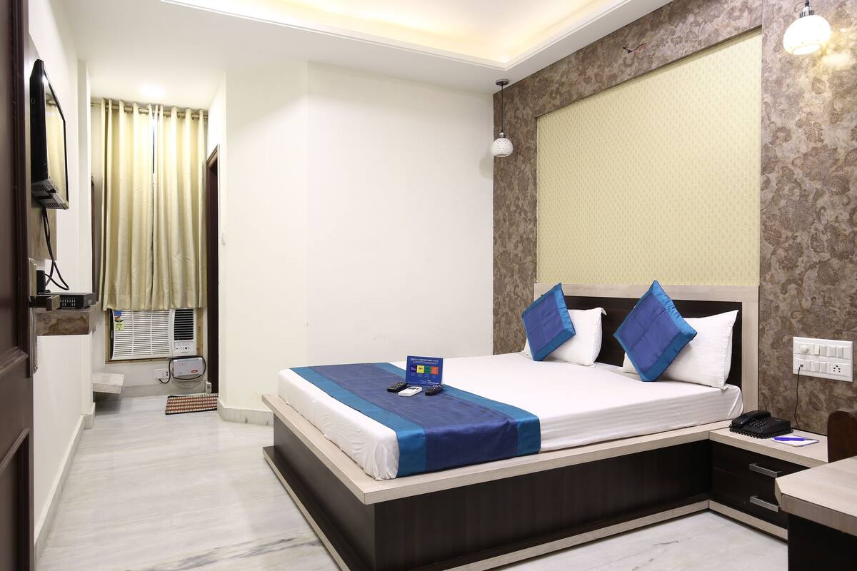 Quarto de hotel com cama, mesa de cabeceira e escrivaninha com cadeira.