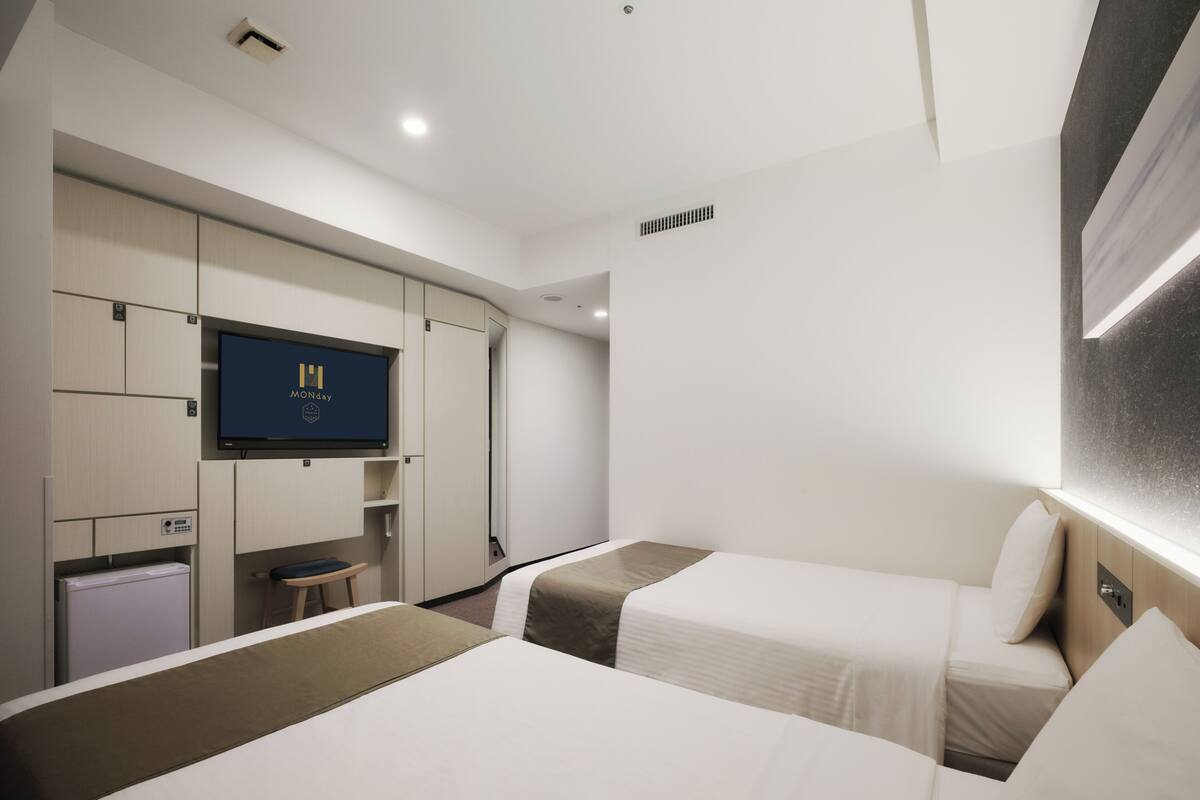 Quarto de hotel com duas camas, televisão, escrivaninha e minibar.
