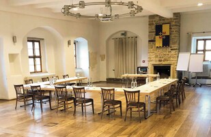 Uma sala de conferência com uma mesa comprida, cadeiras, lareira e parede de pedra.