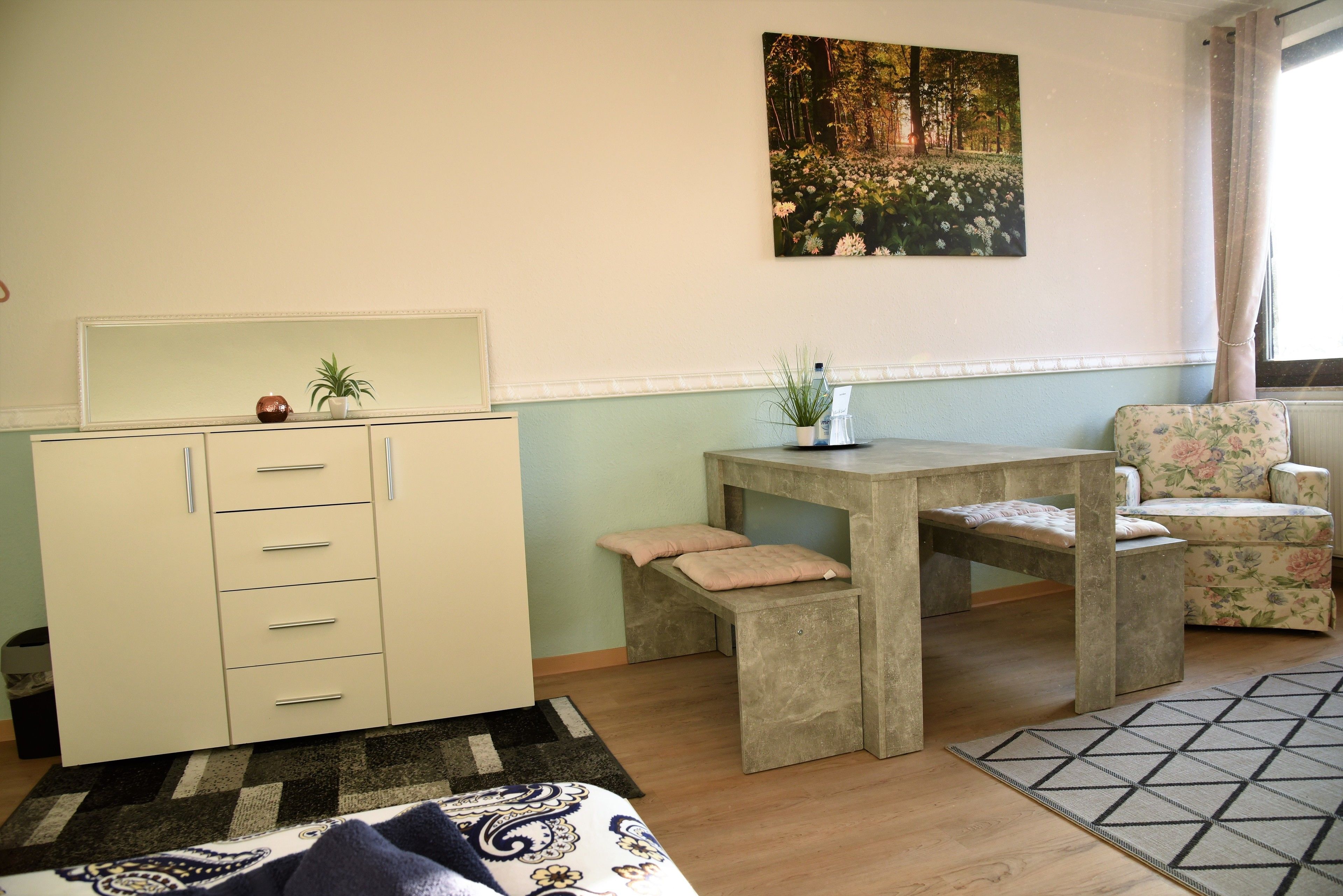 Um quarto com cama, escrivaninha, cadeira, guarda-roupa e um quadro na parede.