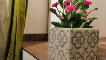 Uma planta em vaso com flores cor-de-rosa sobre um parapeito de madeira.