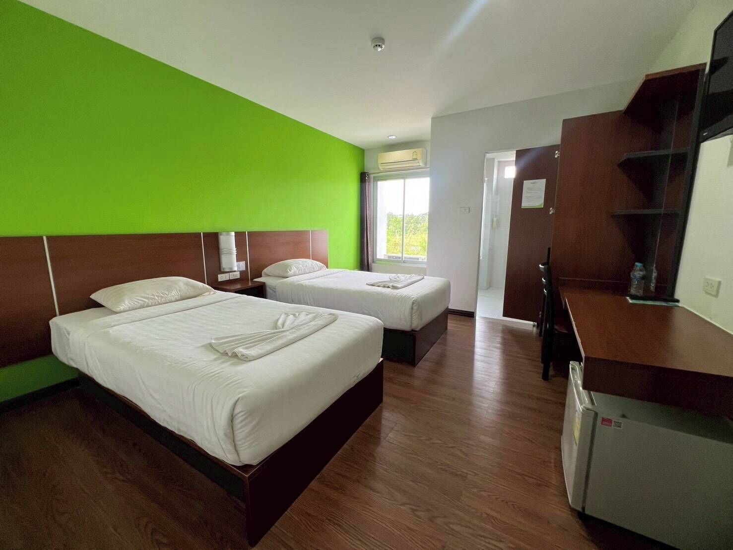 Quarto de hotel com duas camas, uma kitchenette e vista para o exterior.