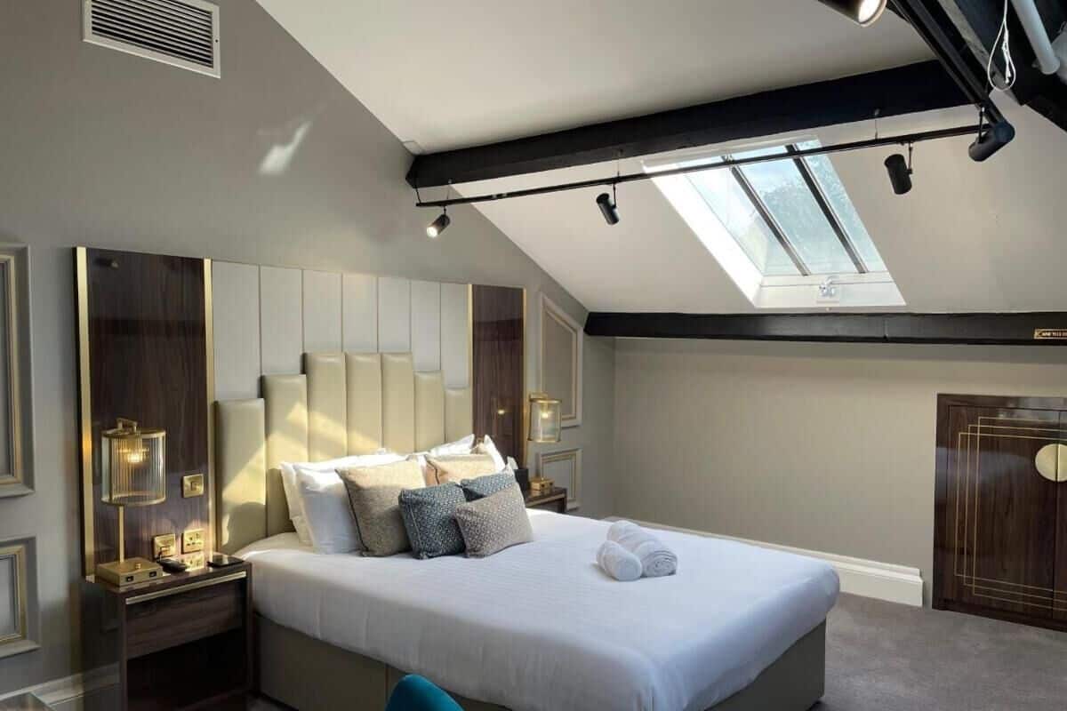 Quarto moderno com uma cama grande, um claraboia e uma mesa de cabeceira com uma luminária.