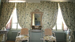 Quarto com duas cadeiras ornamentadas, um espelho e uma mesa.