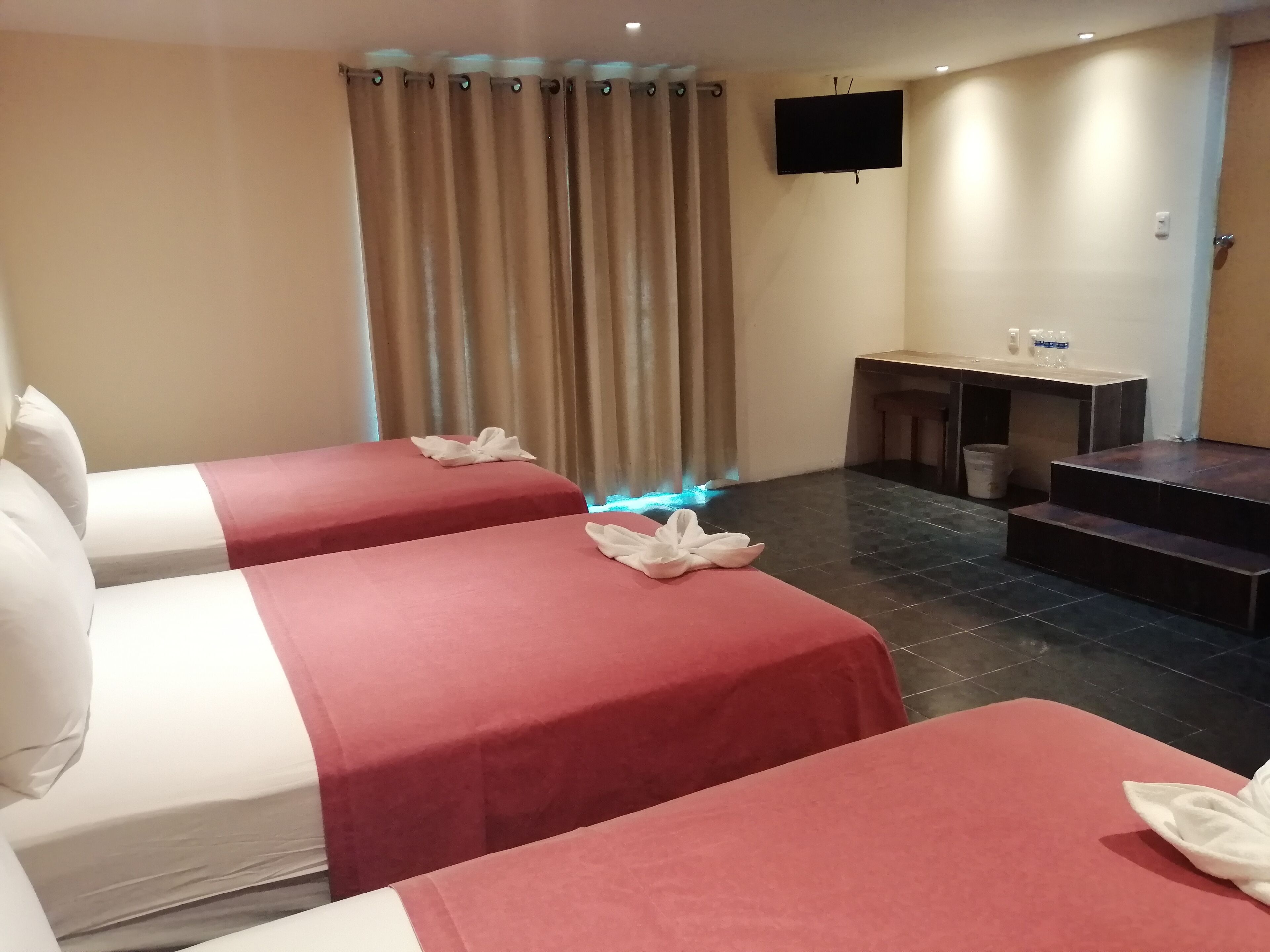 Quarto de hotel com duas camas, televisão, uma mesinha e escadas.