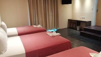Quarto de hotel com duas camas, televisão, uma mesinha e escadas.