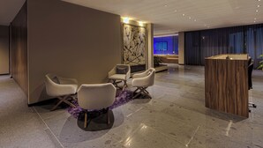 Um lobby moderno com balcão de recepção, área de estar e um painel decorativo.
