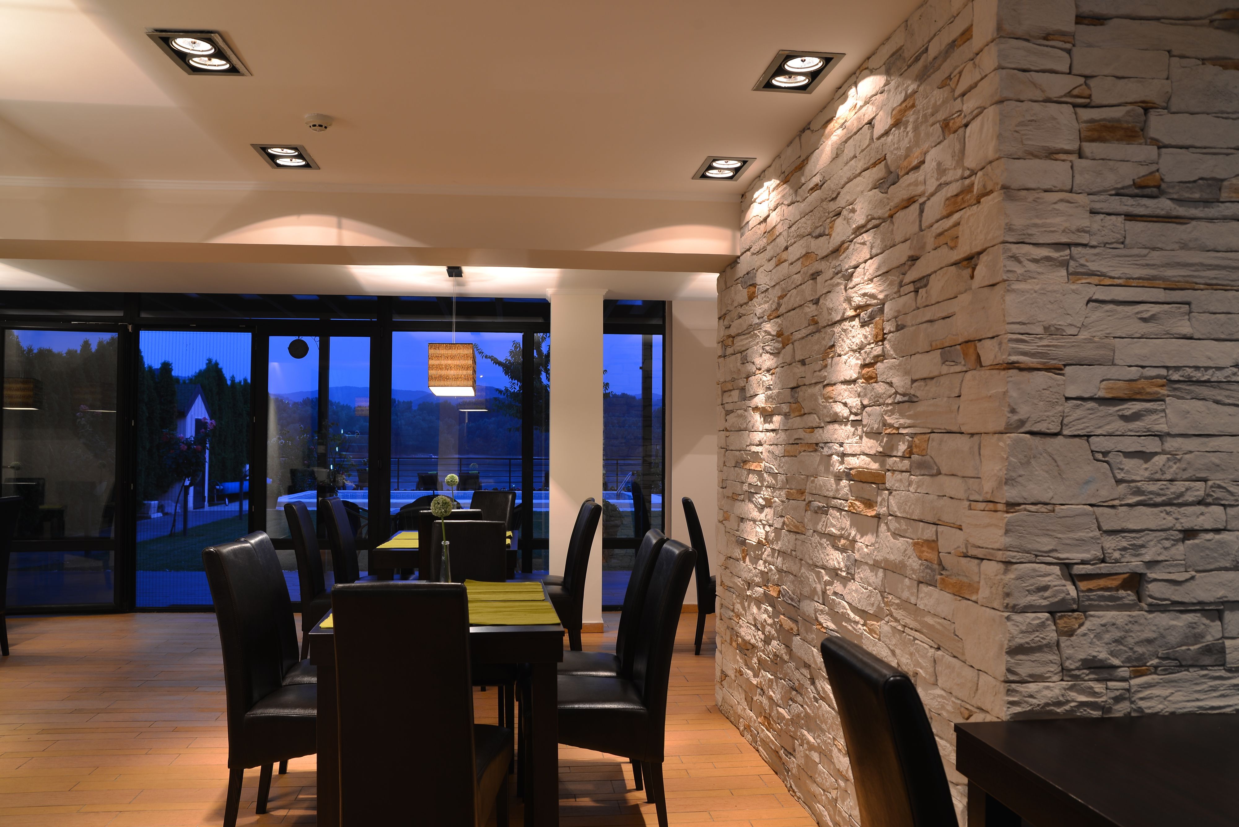 Restaurante com parede de pedra, soalho de madeira e vista para o exterior.