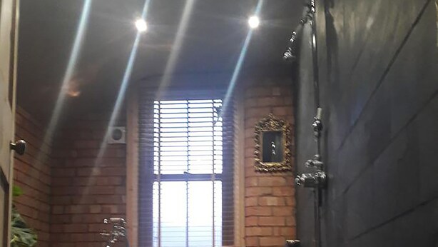 Um corredor estreito com uma banheira grande, uma janela com persianas e um radiador.