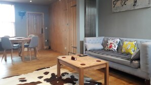 Uma sala de estar moderna com um sofá, uma mesa de centro de madeira e um tapete de couro de vaca.