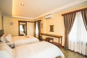 Quarto de hotel com duas camas, uma escrivaninha, um espelho e ar condicionado.