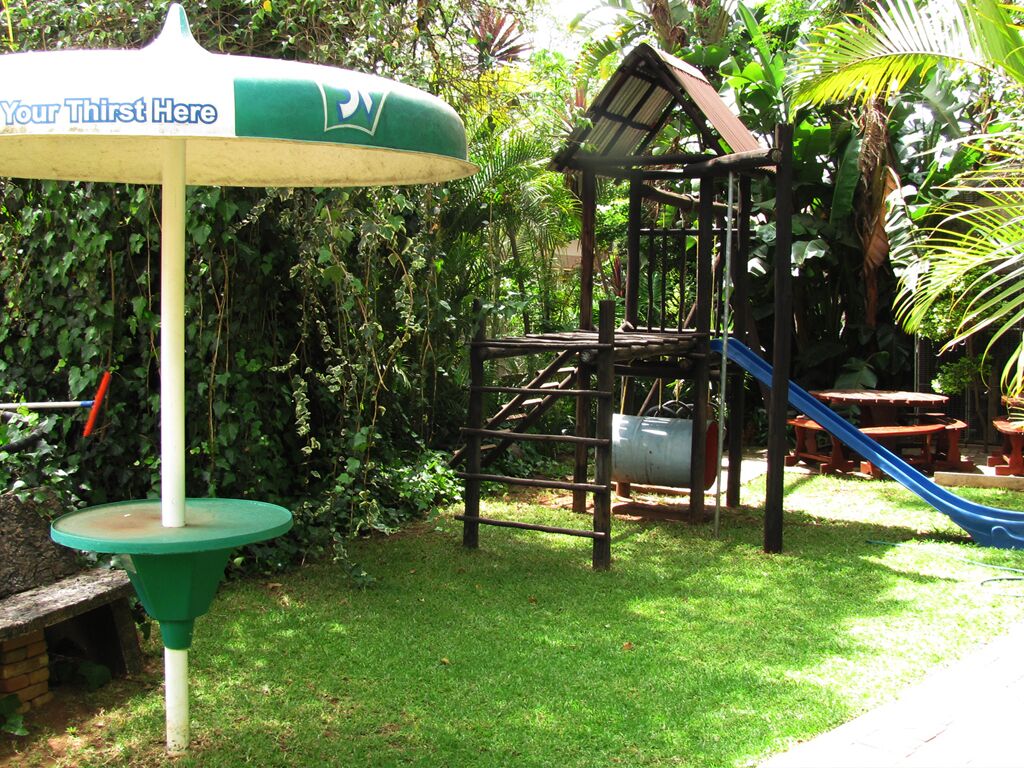 Uma área de recreação infantil com escorrega, estrutura de escalada e bebedouro.