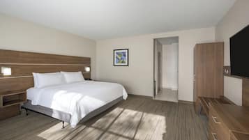 Quarto de hotel moderno com uma cama grande, cabeceira de madeira, televisão de tela plana e guarda-roupa.
