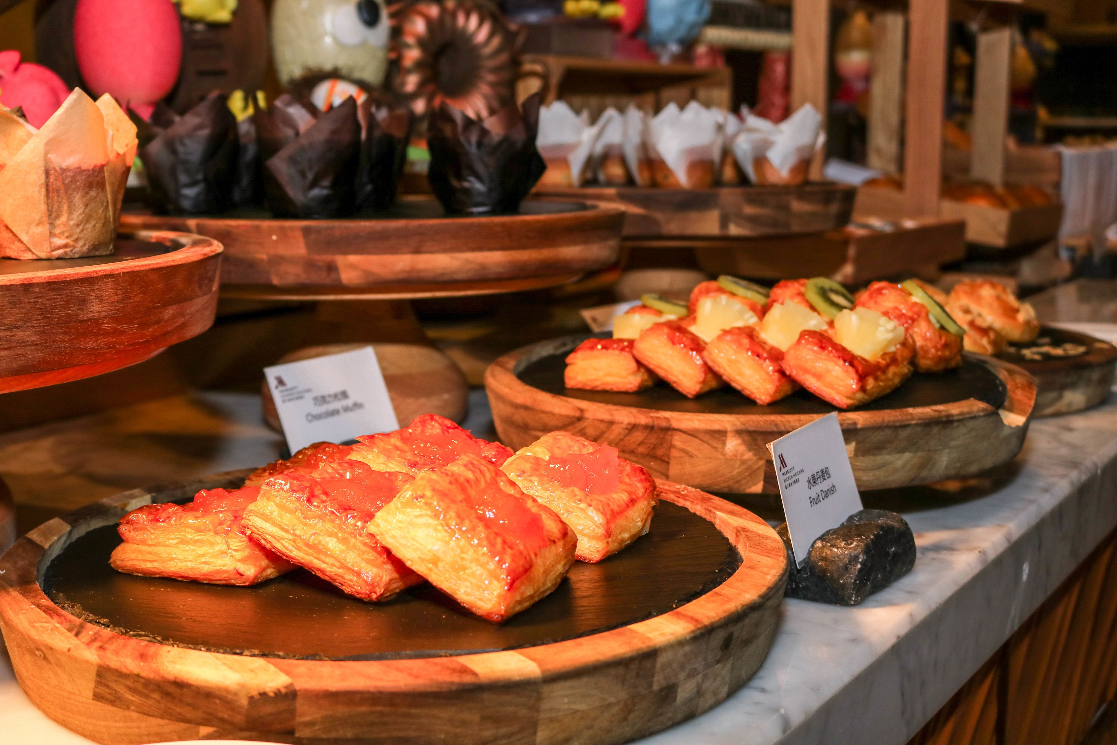 Vitrine de pastelaria com diversos doces e sobremesas em tábuas de madeira.
