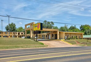 Um motel com um letreiro chamativo 'Super 8', serviço por drive-thru e estacionamento.