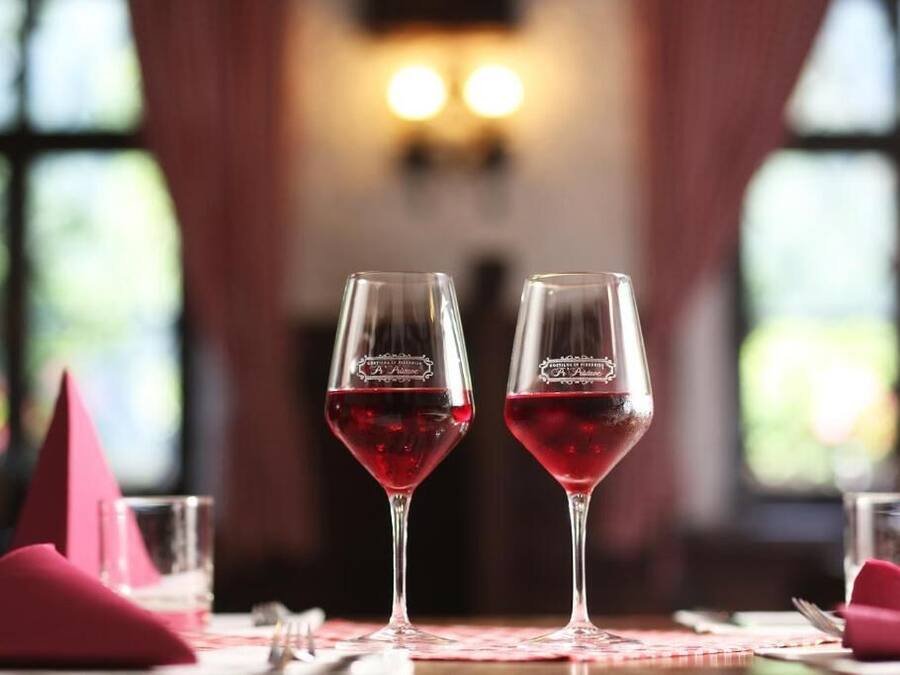 Duas taças de vinho sobre uma mesa com um guardanapo vermelho, uma taça com vinho tinto e um guardanapo vermelho triangular.