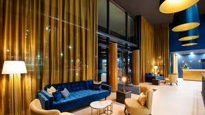 Um hall moderno com um sofá azul, poltronas bege e uma mesa de centro redonda.