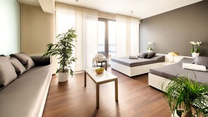 Uma sala de estar moderna com sofá, mesa de centro e mesa de jantar. Há plantas em vasos e vista para o exterior.
