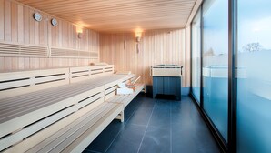 Uma sala de sauna com bancos de madeira e parede de vidro.