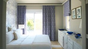 Quarto com cama grande, cómoda, espelho e janela com cortinas.