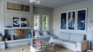 Uma sala de estar moderna com uma mesa de centro de vidro, um sofá e arte decorativa na parede.