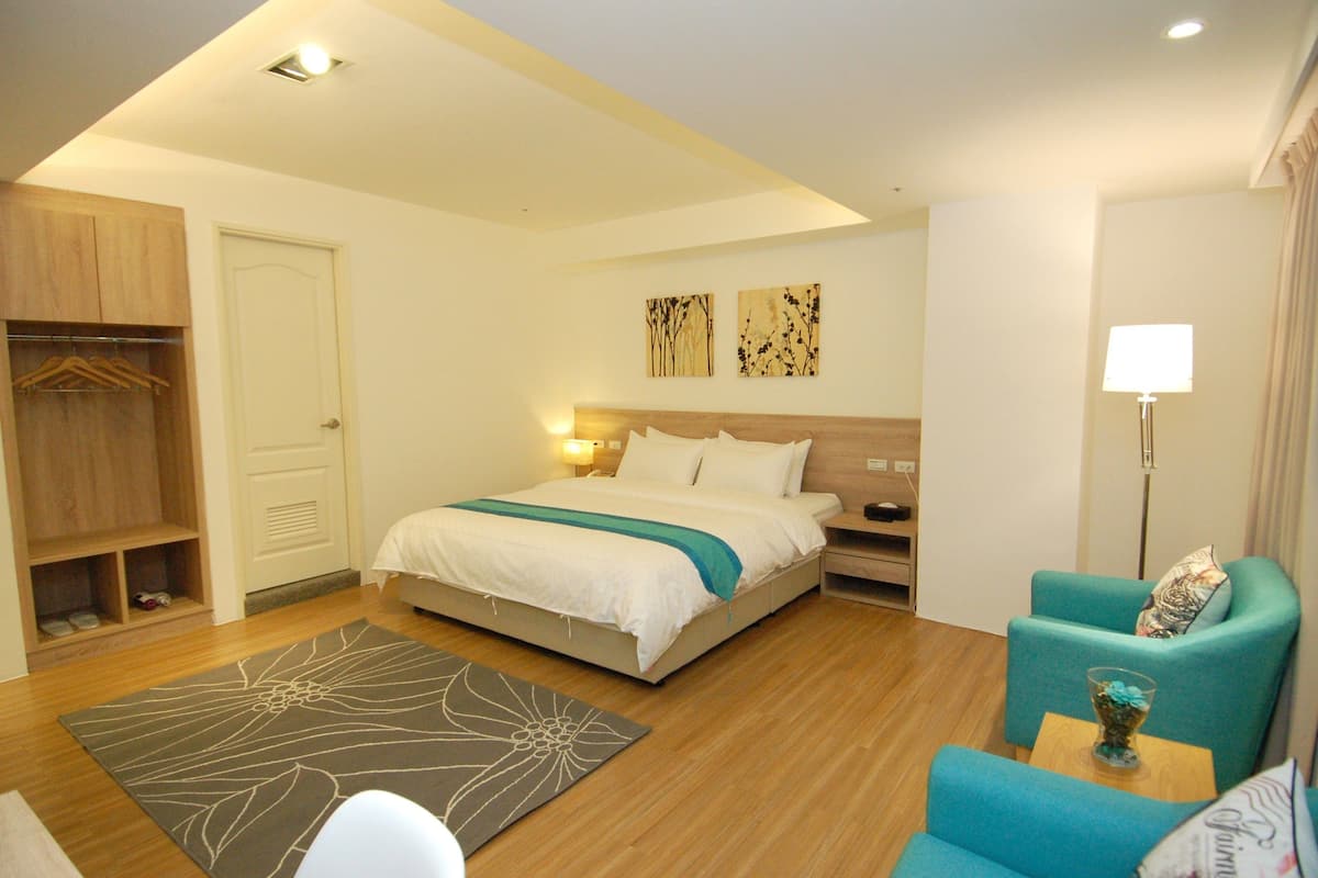 Quarto de hotel com cama, área de estar, guarda-roupa e obras de arte na parede.