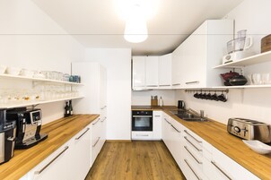 Uma cafeteira/bule, um frigorífico no espaço comum 