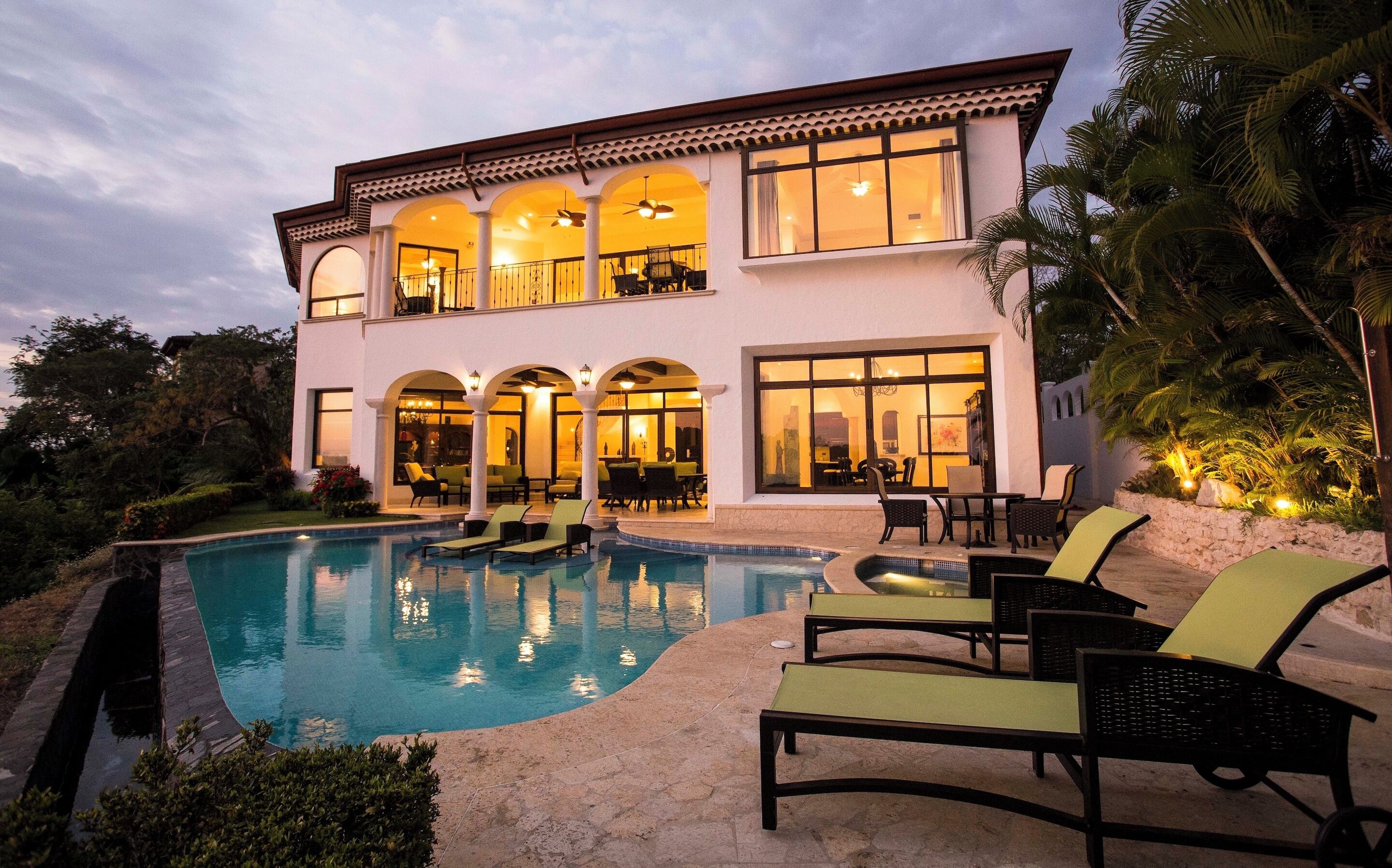 Uma casa de dois andares com piscina, área de estar externa e varanda.
