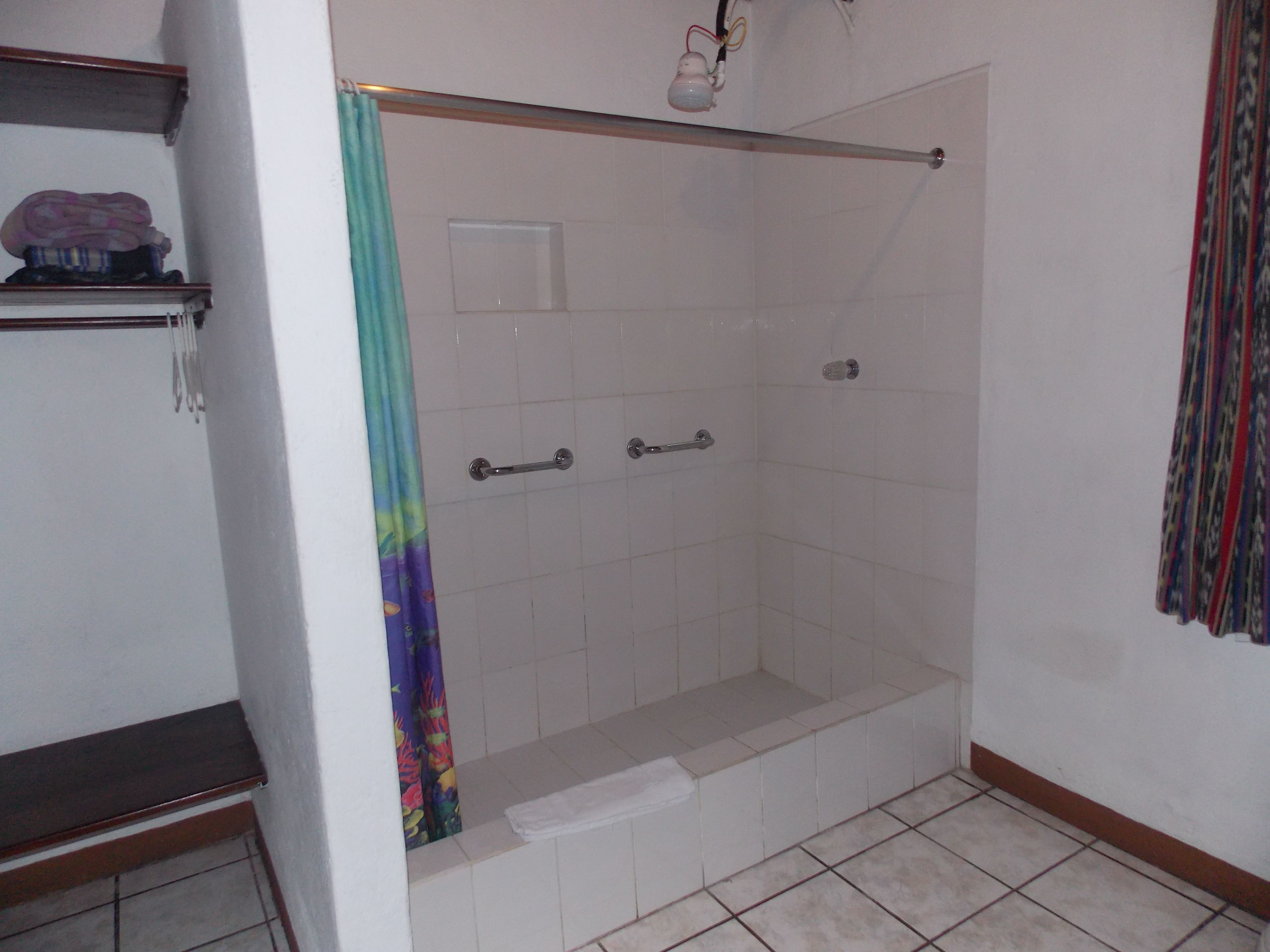 Um chuveiro com porta de vidro, um porta-toalhas e uma prateleira com toalhas.