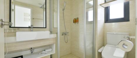 Uma casa de banho moderna com chuveiro em cabine de vidro, lavatório branco e sanita com suporte para toalhas de papel.