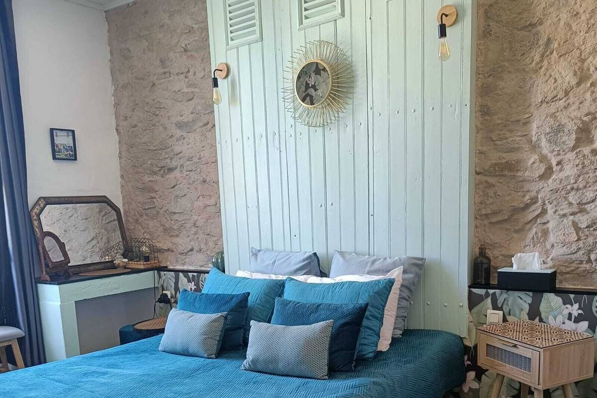 Quarto com cama, escrivaninha e luminária fixada na parede.