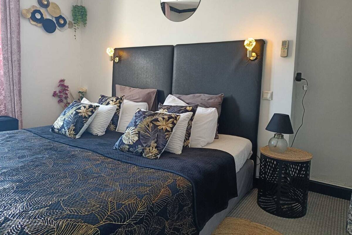Quarto bem arrumado com uma cama grande, uma mesa de cabeceira com abajur e um espelho na parede.