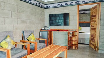 Um quarto pequeno e acolhedor, com sofá, mesa de madeira e uma pequena cozinha compacta.