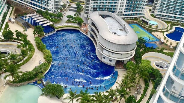 Uma piscina grande rodeada por palmeiras e edifícios modernos.