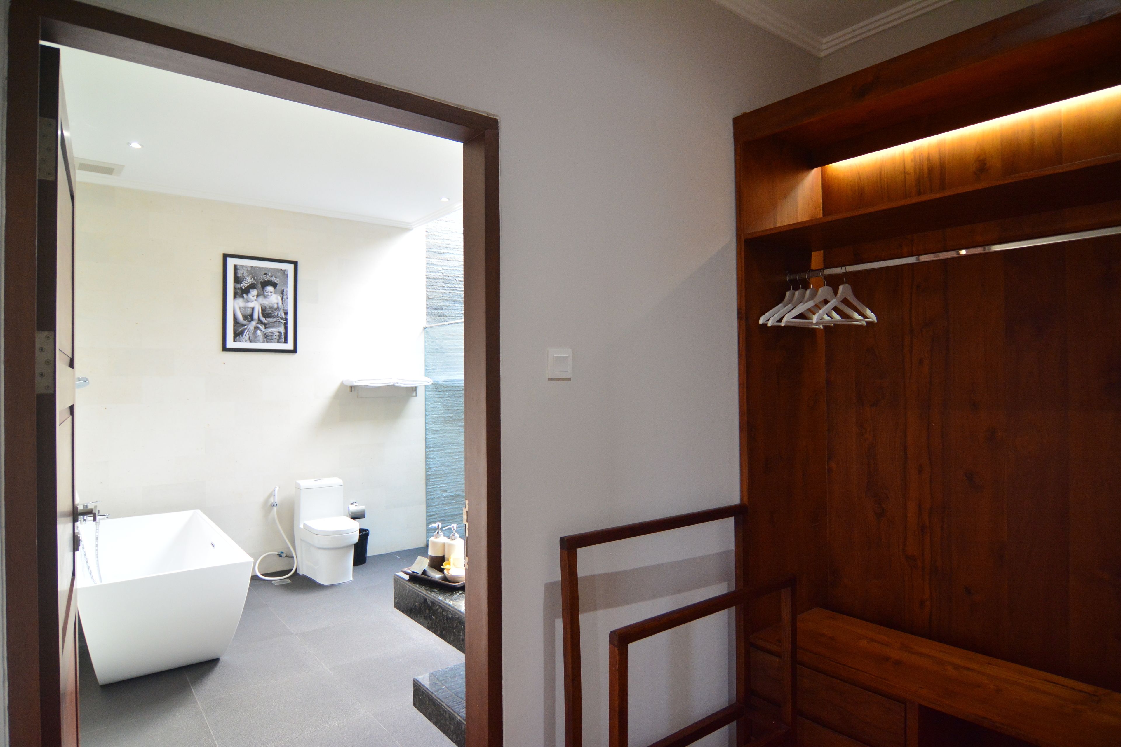 Uma casa de banho moderna com banheira, sanita e toucador de madeira com porta-toalhas.