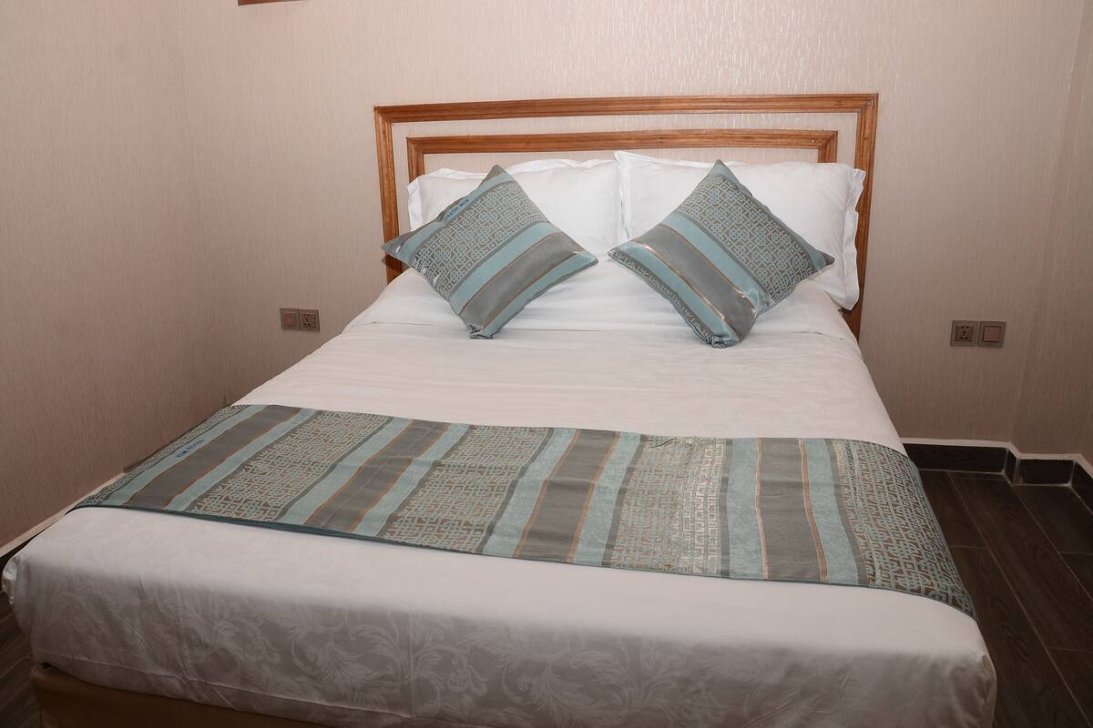 Uma cama bem arrumada com colcha estampada e dois travesseiros.