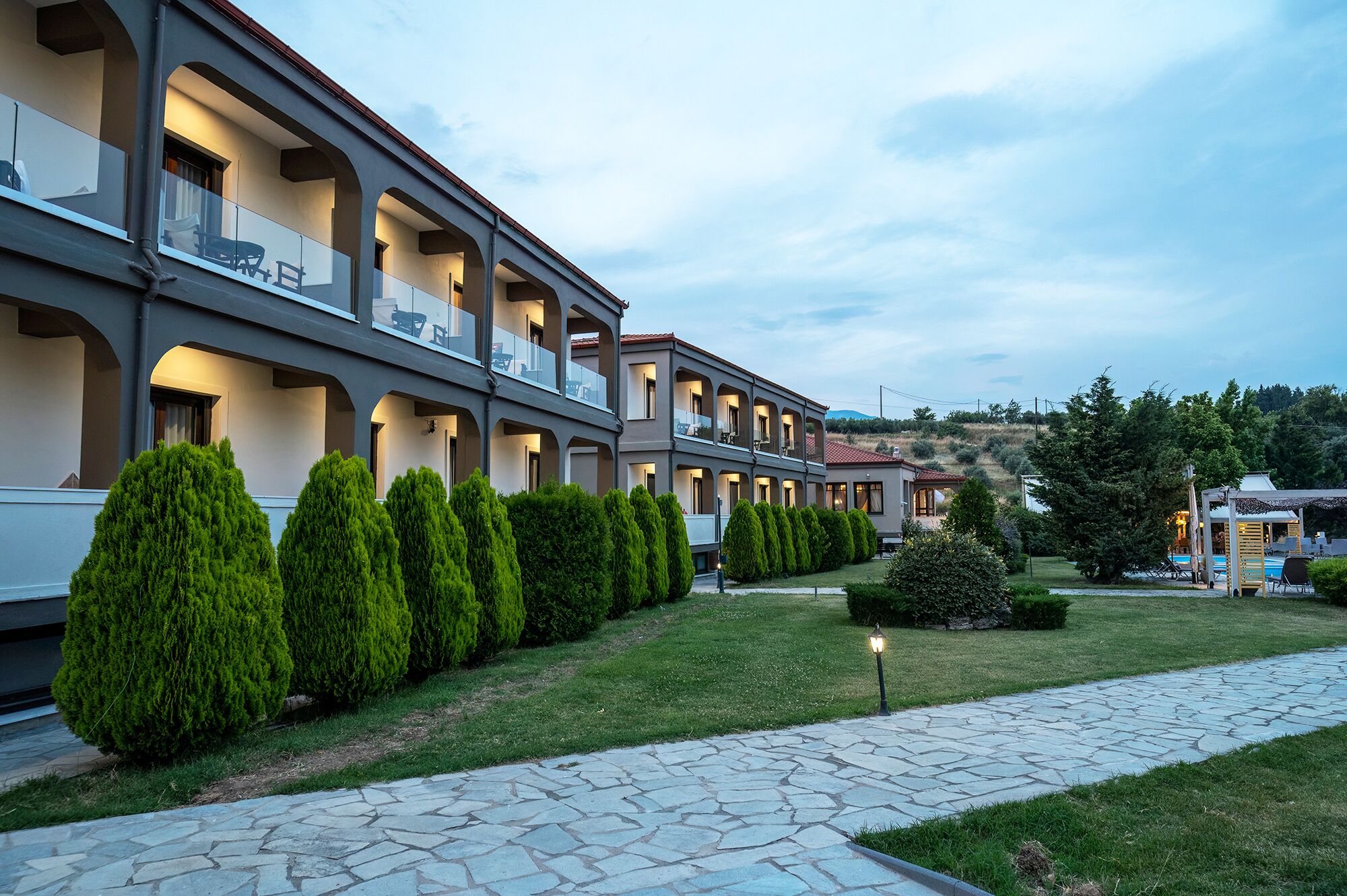 Um hotel com várias varandas, um jardim bem cuidado e área de piscina.