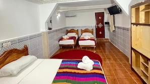 Quarto de hotel com duas camas, uma TV fixada na parede e um guarda-roupa de madeira.
